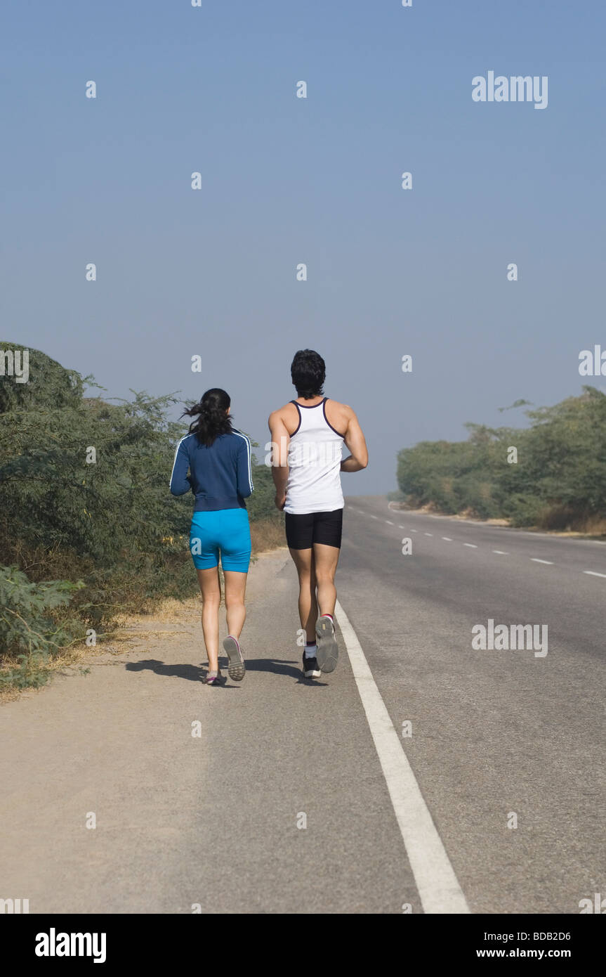Rear view of a couple jogging at the roadside Stock Photo - Alamy