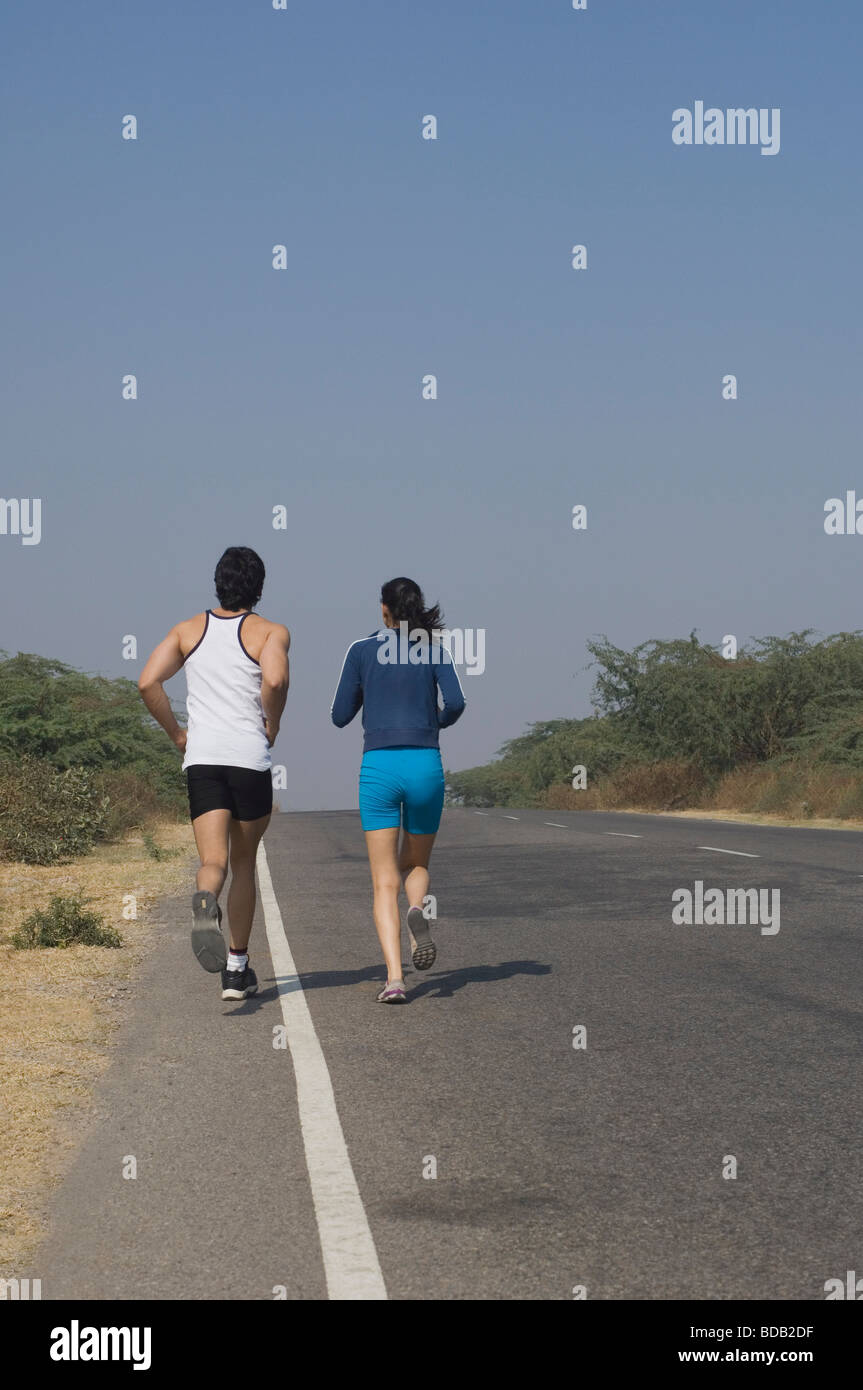 Rear view of a couple jogging at the roadside Stock Photo - Alamy
