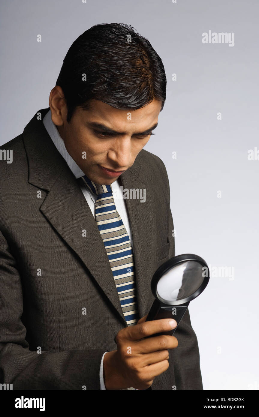 Businessman looking through magnifying glass Stock Photo - Alamy