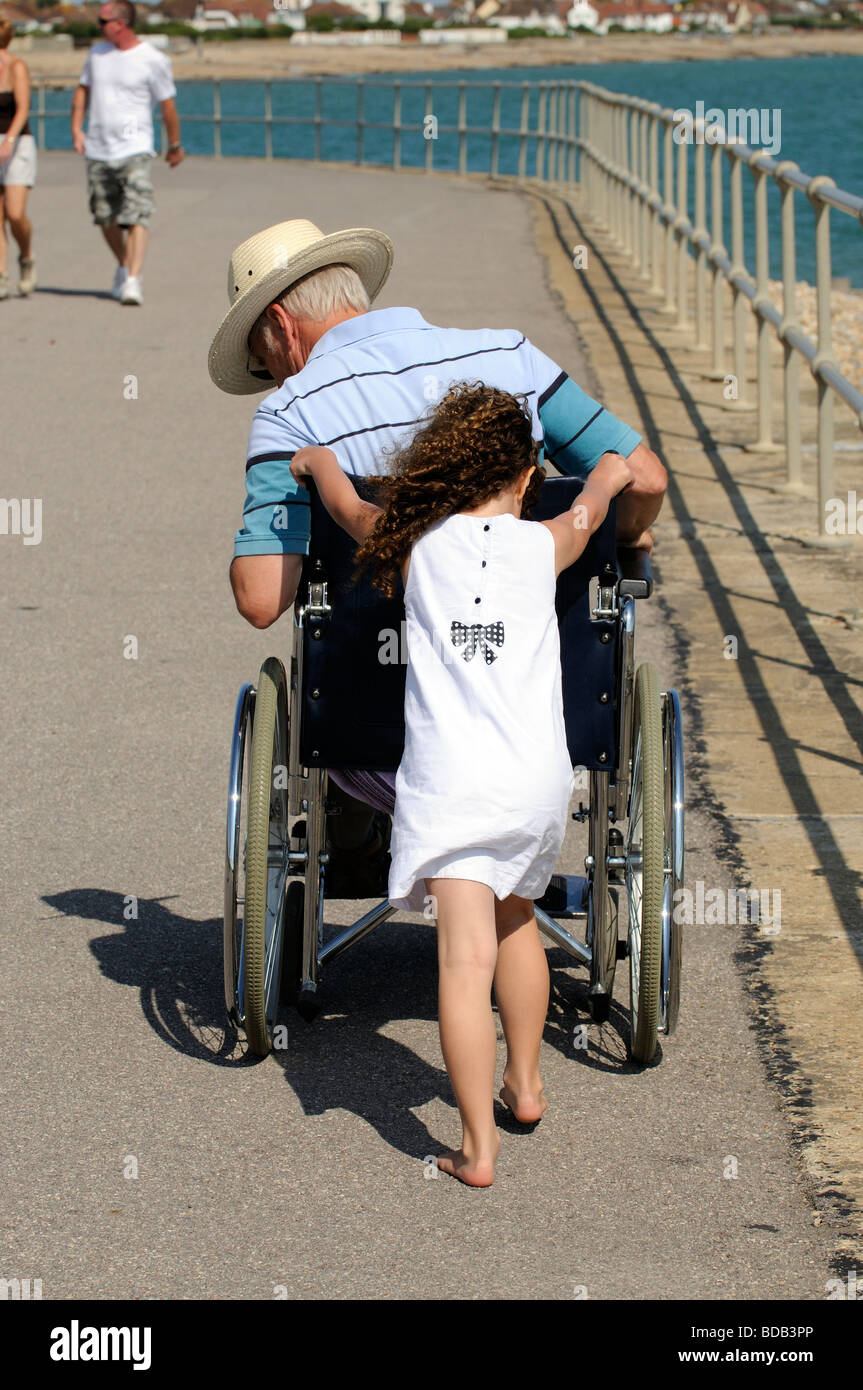 Little girl pushing an adult wheelchair user along the prom in Bognor ...