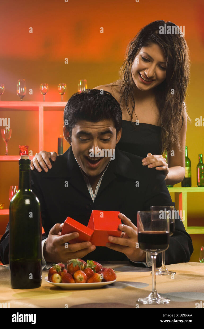 Woman giving a present to her boyfriend in a bar Stock Photo - Alamy