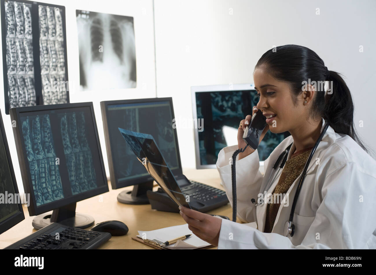 Female doctor examining an X-Ray and talking on the telephone Stock ...
