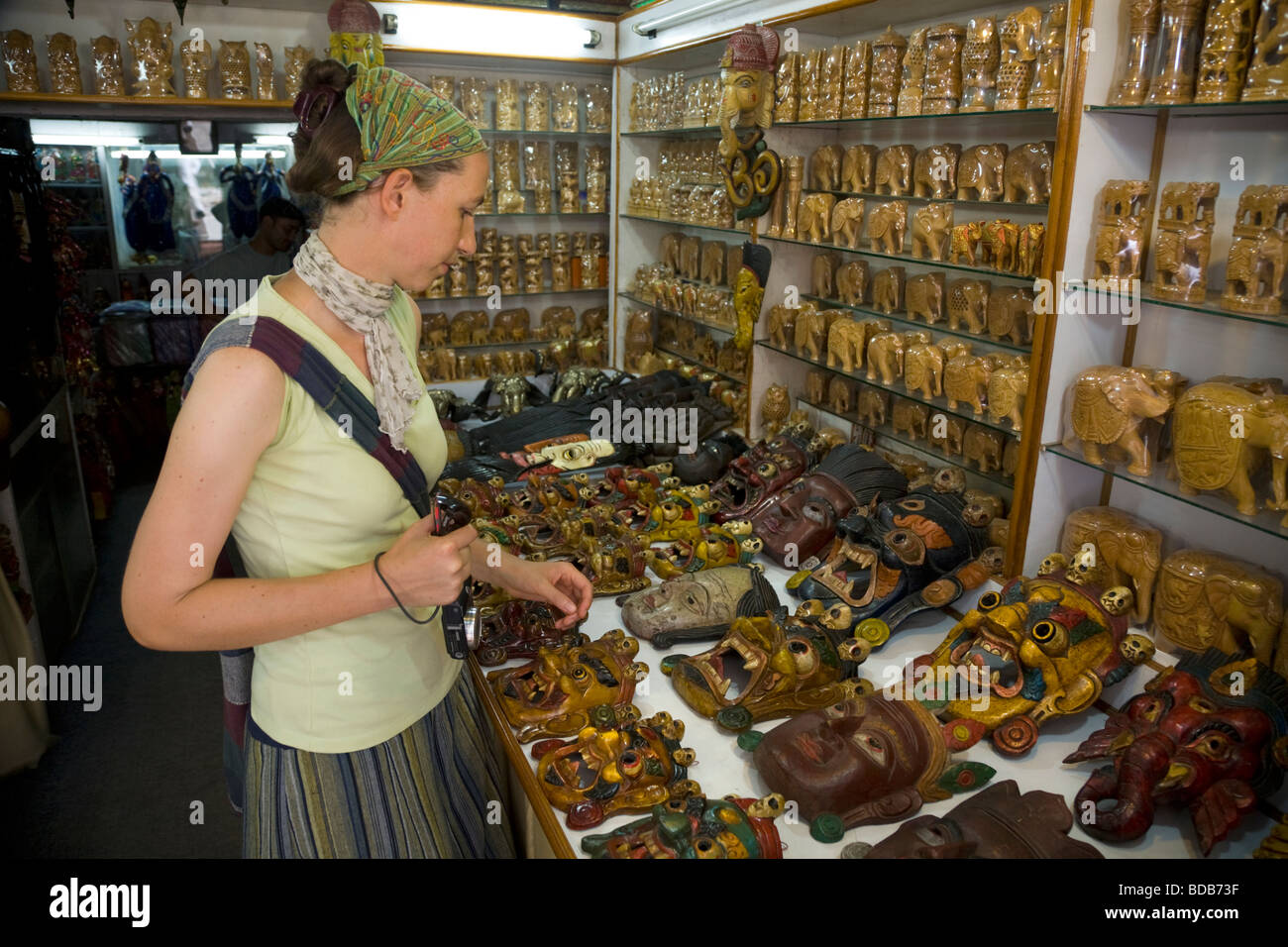 Western tourist examines souvenir mask present for sale at gift shop ...