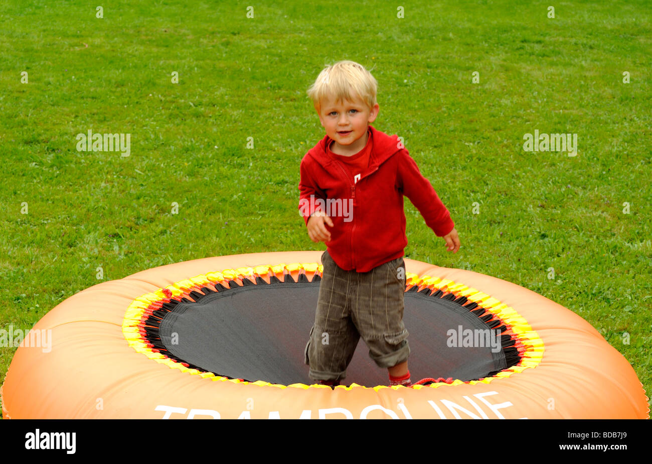 Blond Child Boy Jumping on orange Trampoline in Yard Stock Photo - Alamy
