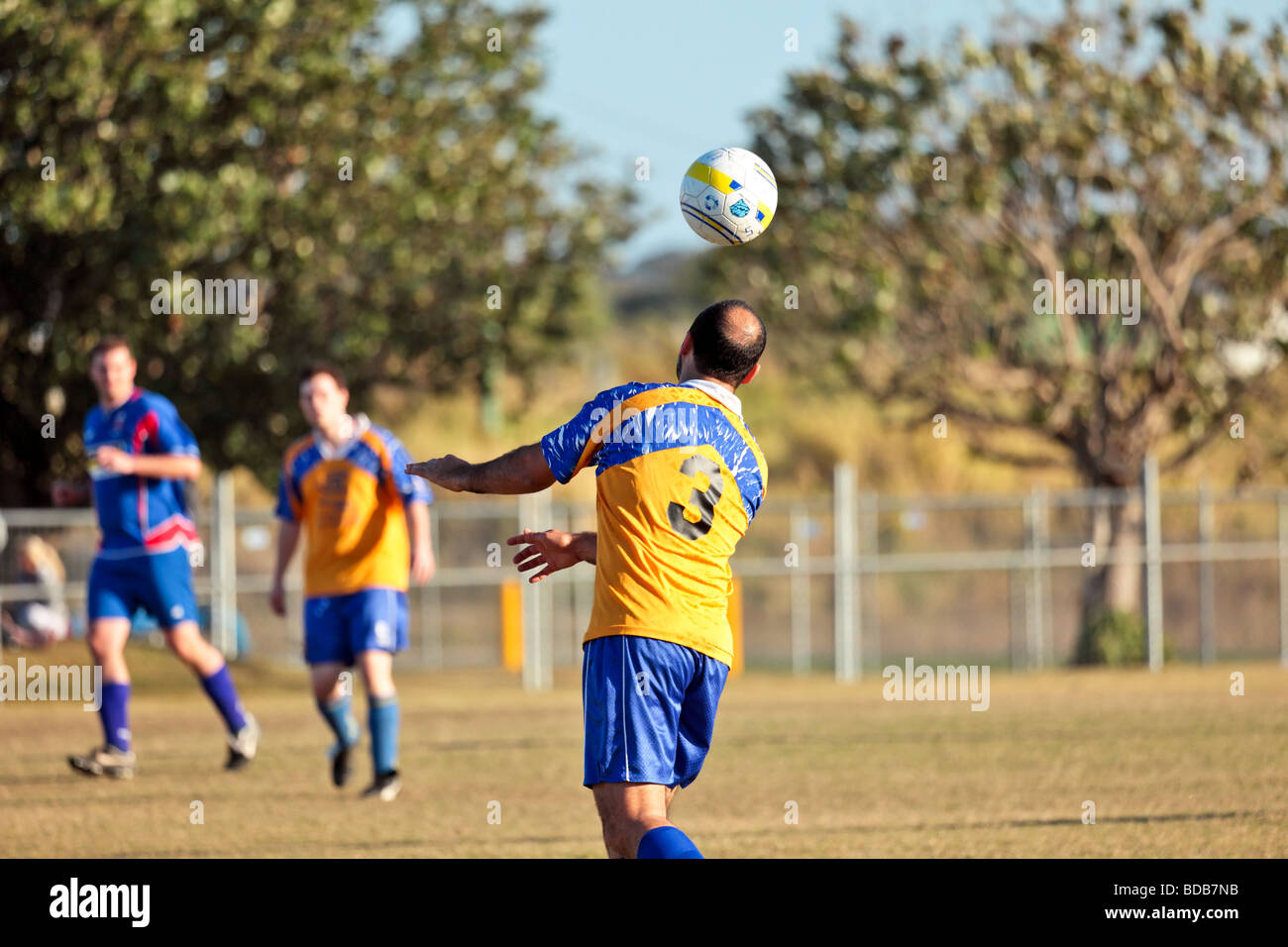 Two soccer teams playing a match heading the ball dribbling and kicking ...