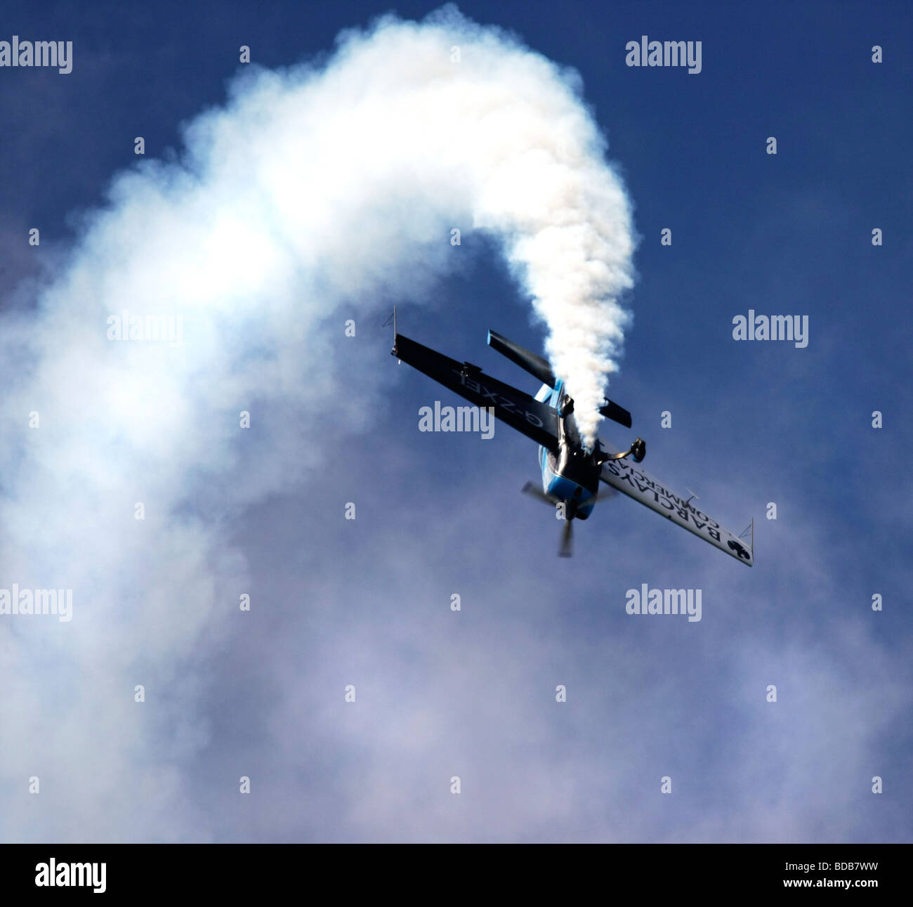 Blue aerobatic plane doing a loop the loop roll and leaving a large ...