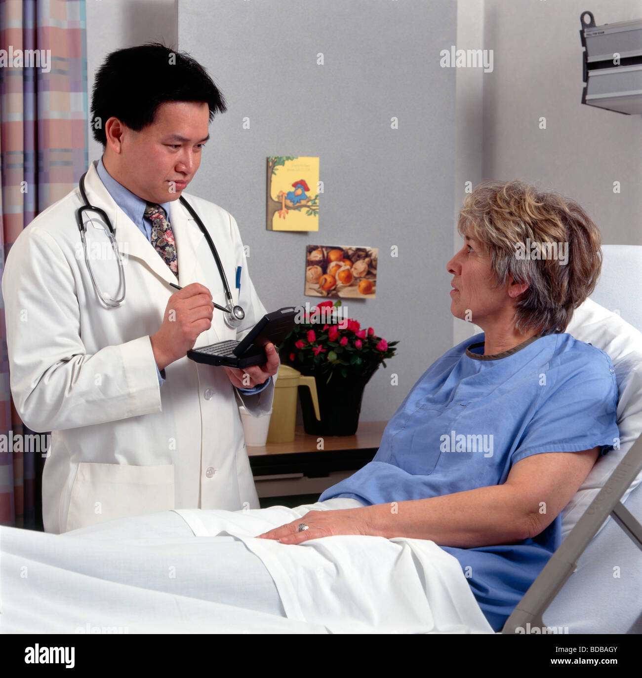 An Asian male physician uses a PDA personal digital assistant as does ...