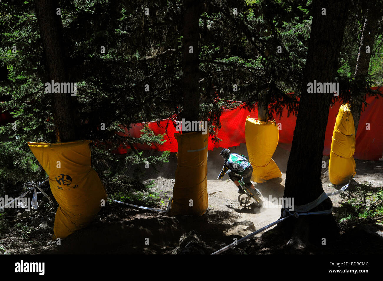 A mountain biker takes a dusty corner downhill trail through padded ...
