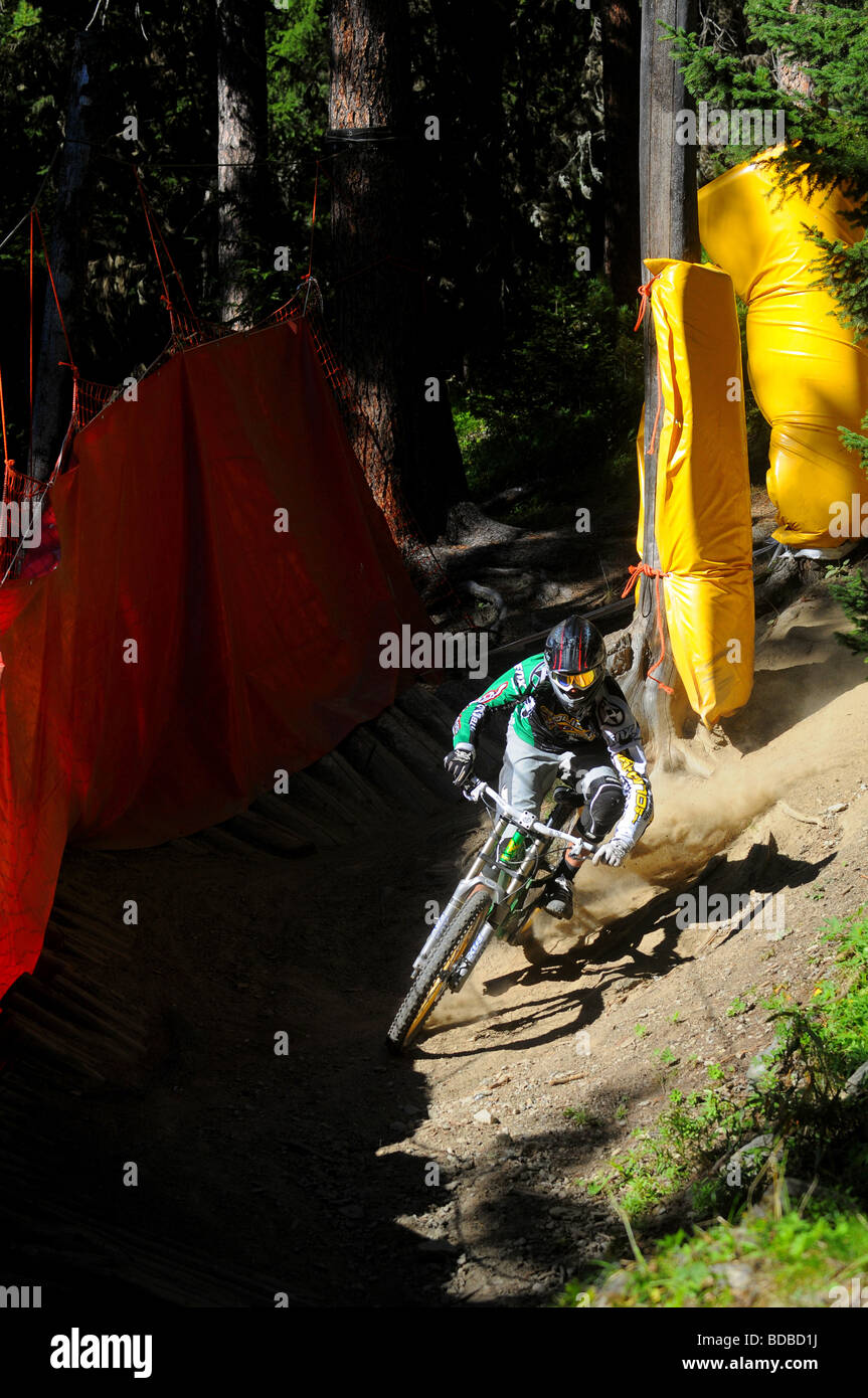 A mountain biker takes a dusty corner downhill trail through padded ...