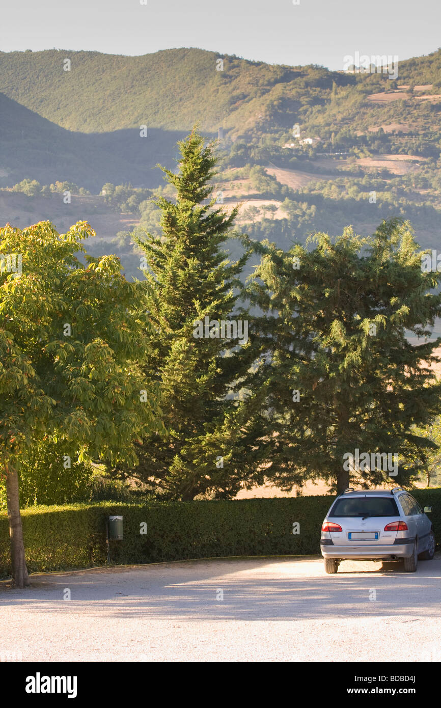 Car parked on a gravel driveway near Norcia, Italy, with lush evergreen ...