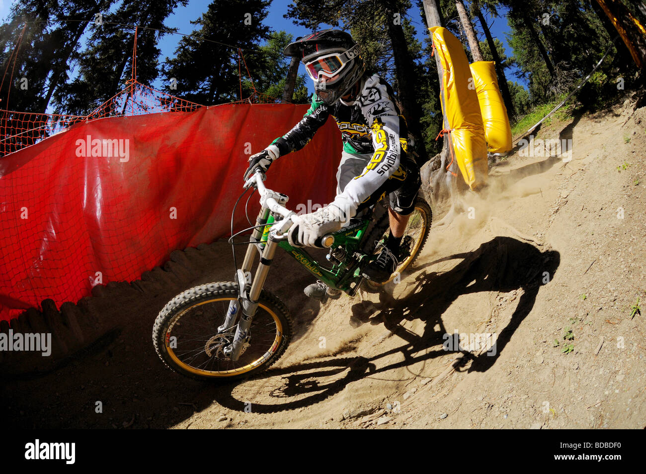 A mountain biker takes a dusty corner downhill trail through padded ...