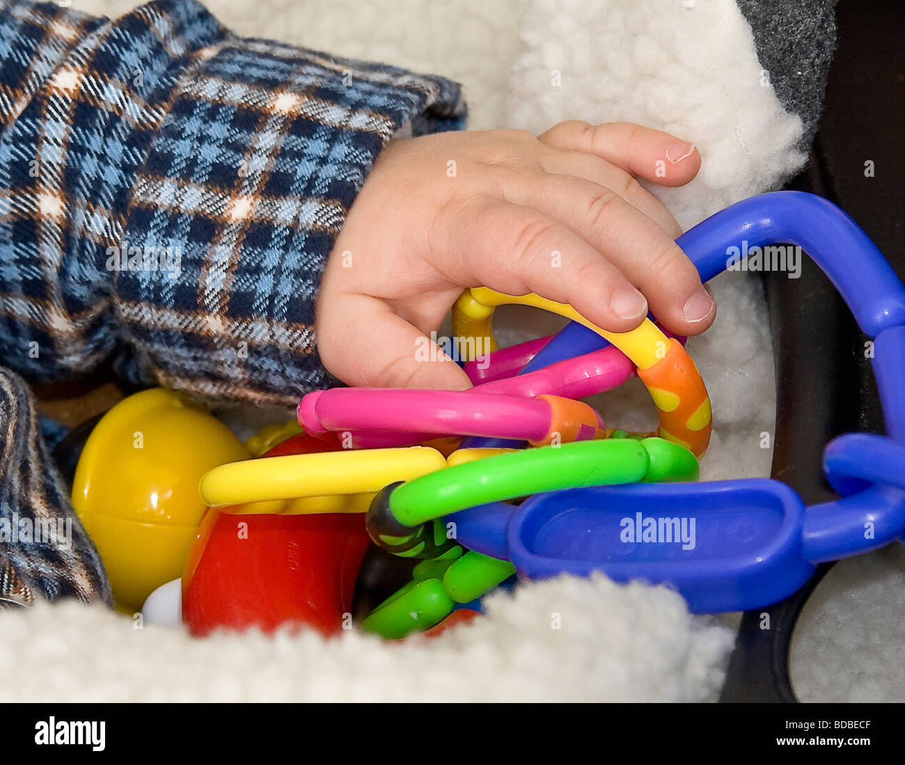 Baby's hand and forearm with blue long sleeves, reaching for colorful ...
