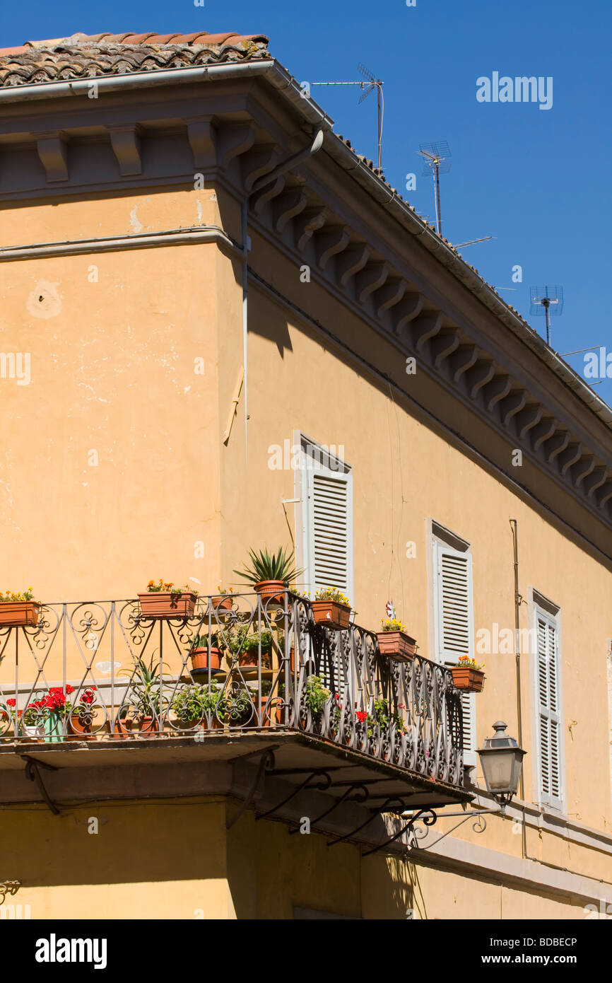 Traditional Tuscan building with ornate balcony filled with flower pots ...