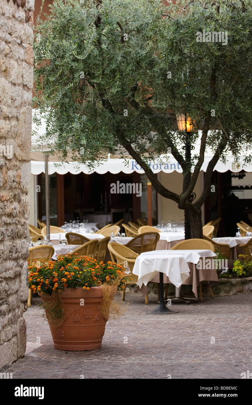Charming outdoor restaurant patio with wicker chairs and tables, terracotta flowerpot with ...