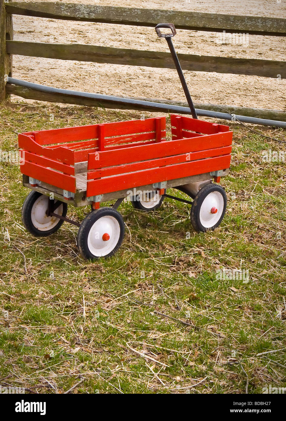 child's wheel cart, red, on green grass and wood fence in background ...