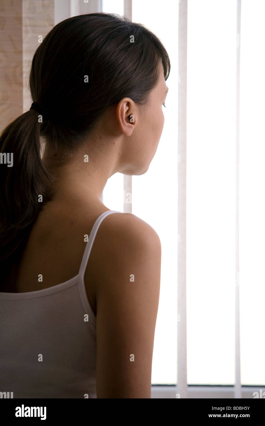 rear view of young woman looking through window Stock Photo - Alamy