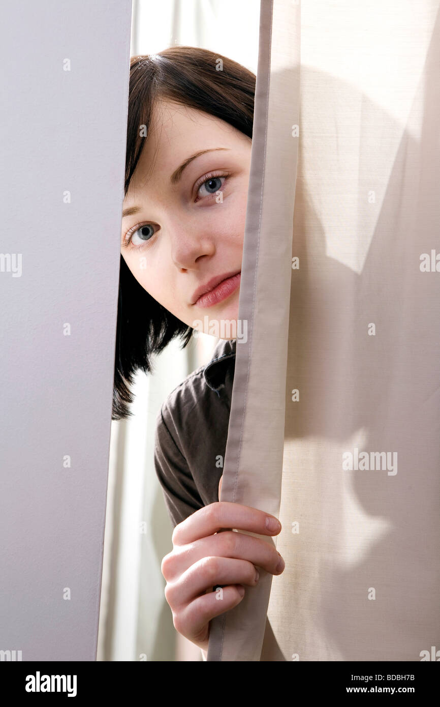 portrait of young woman peeking through curtain of changing room Stock ...