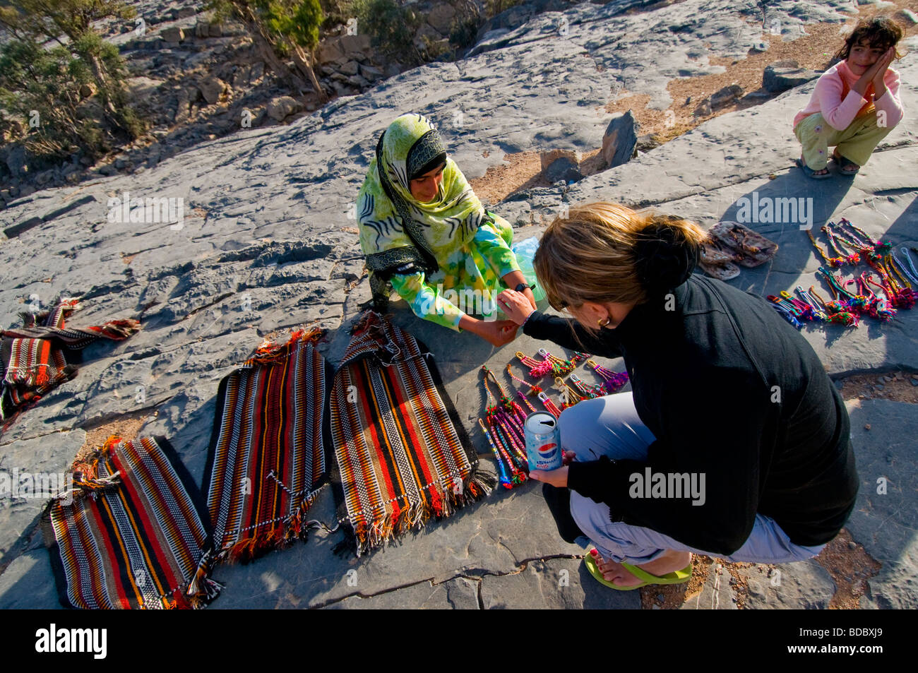Tourist buying handicrafts from bedouin children Jabel Shams Oman Stock ...