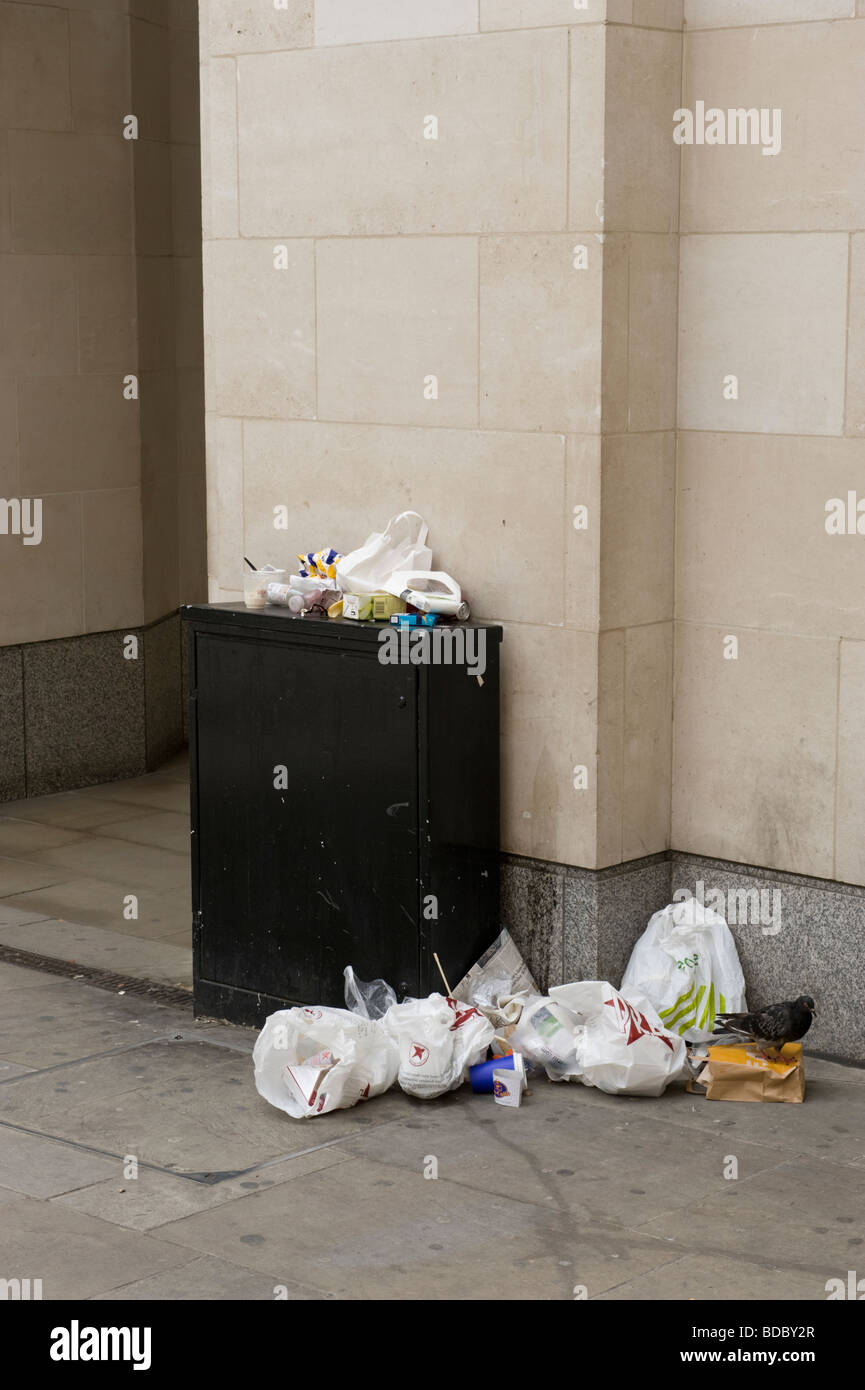 trash, debris, rubbish and plastic bags on the ground around a litter ...