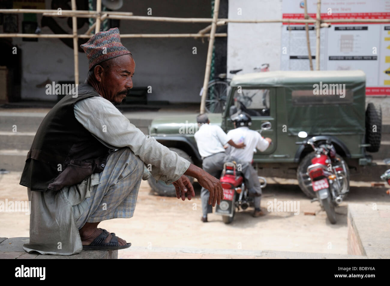 man sitting on haunches on edge of stone platform contemplate ...