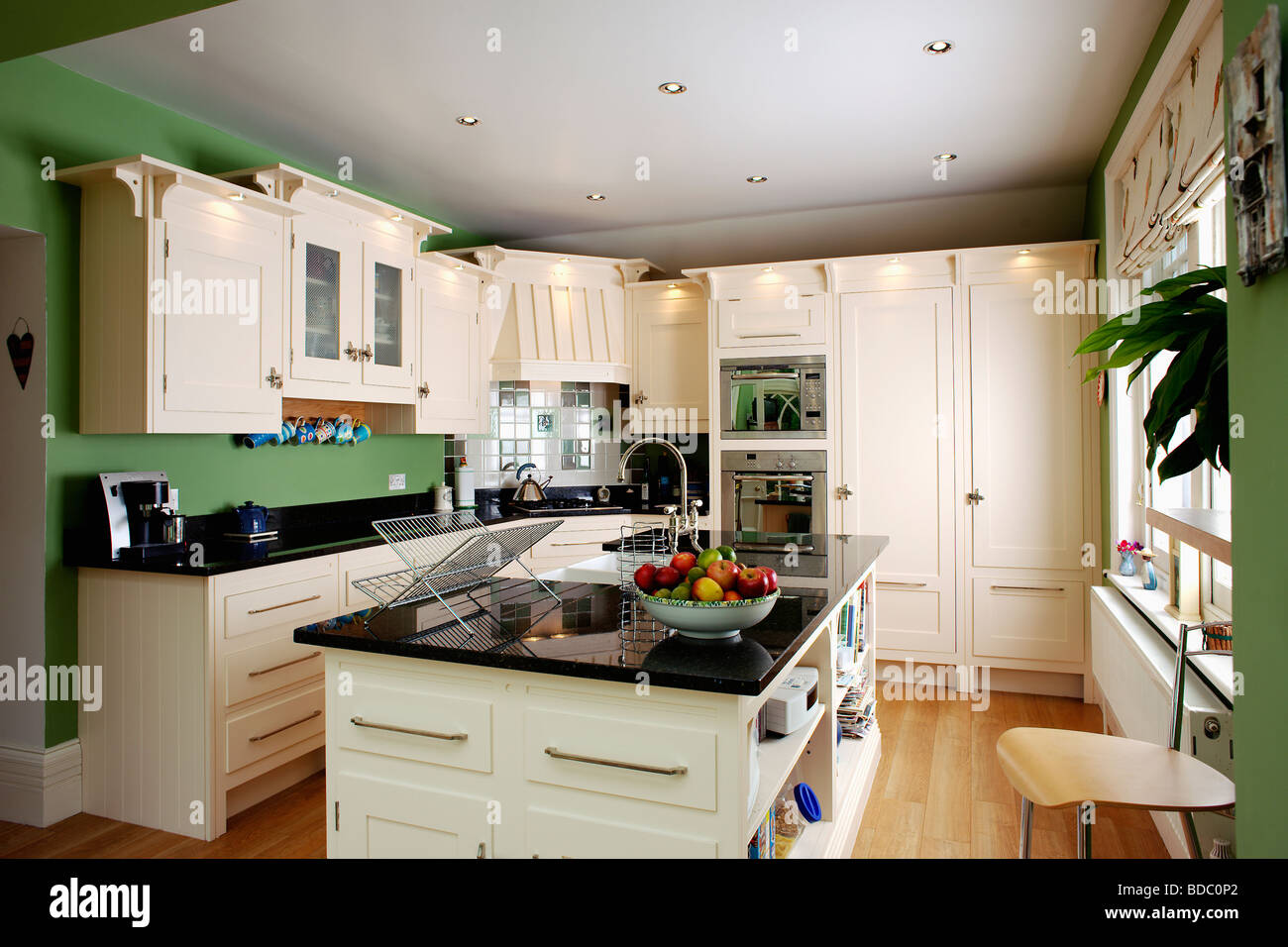 Granite topped island unit in green kitchen with white fitted units ...