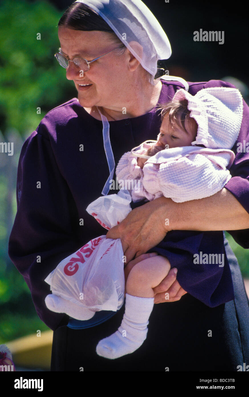 Amish Mother, grandmother holds baby while shopping at suburban garage ...