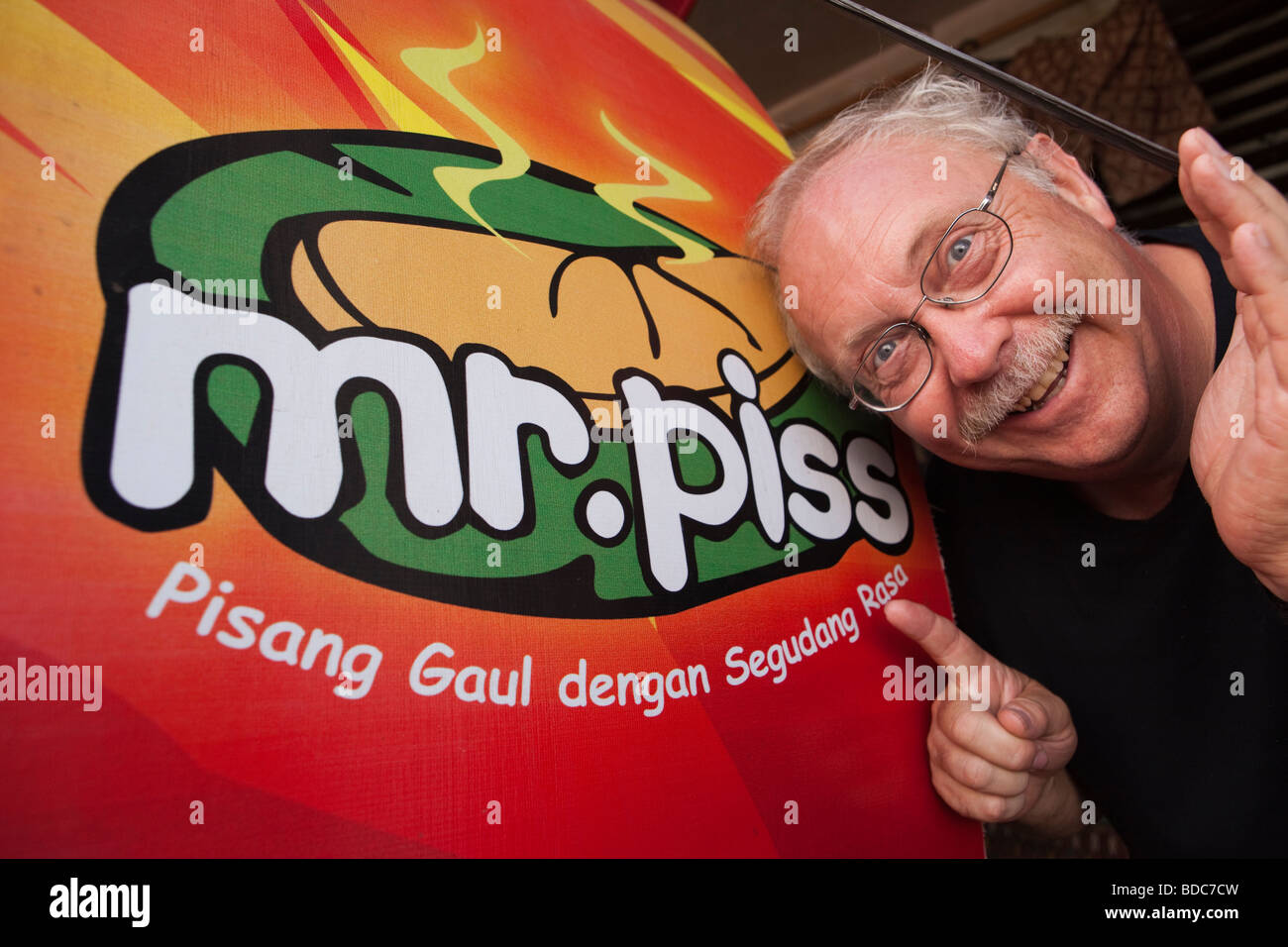 Indonesia, Sulawesi, Tana Toraja, Rantepao, middle aged man pointing at amusing Mr Piss sign ...
