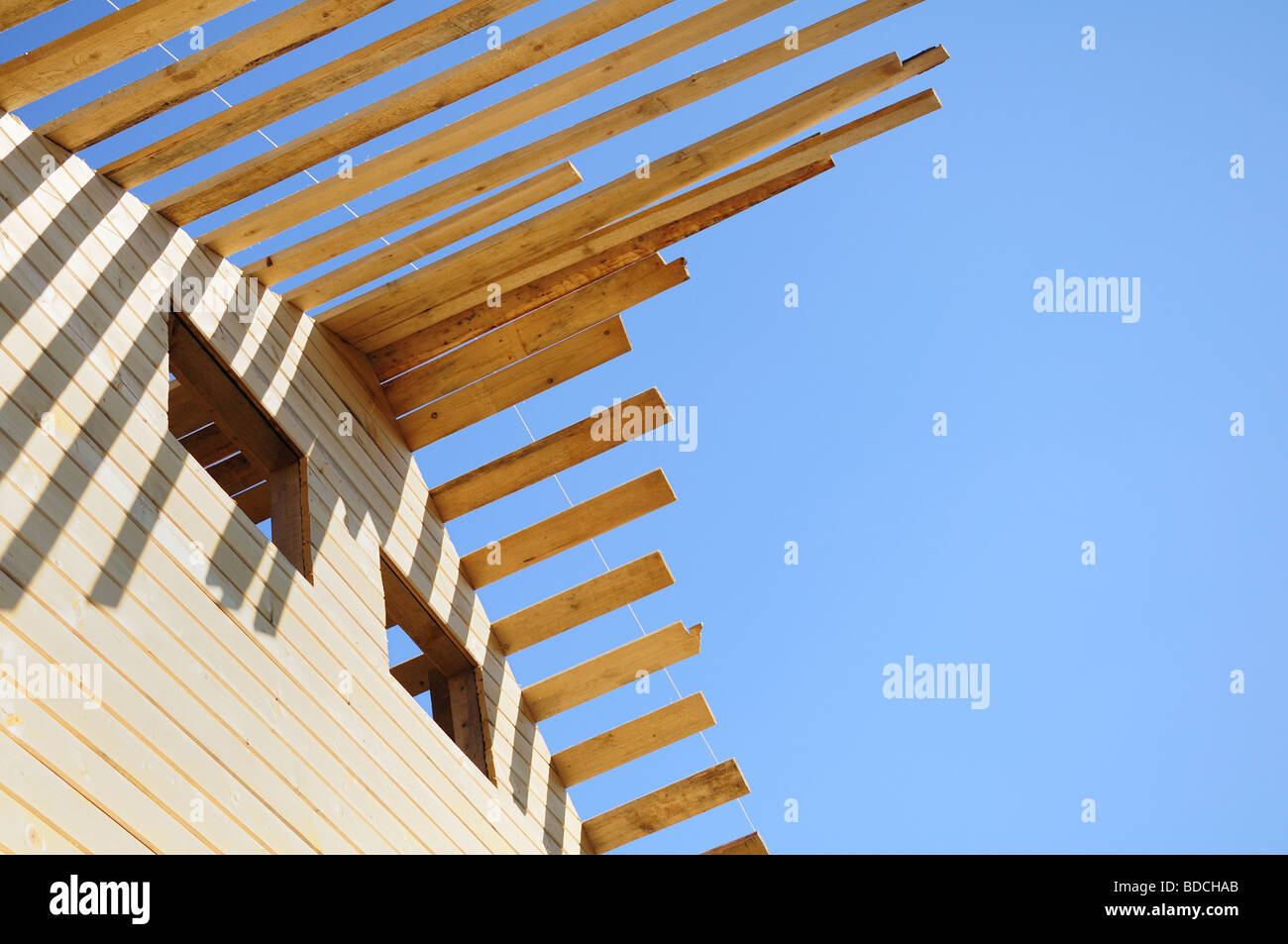The unfinished wooden roof and empty windows at the blue sky background ...