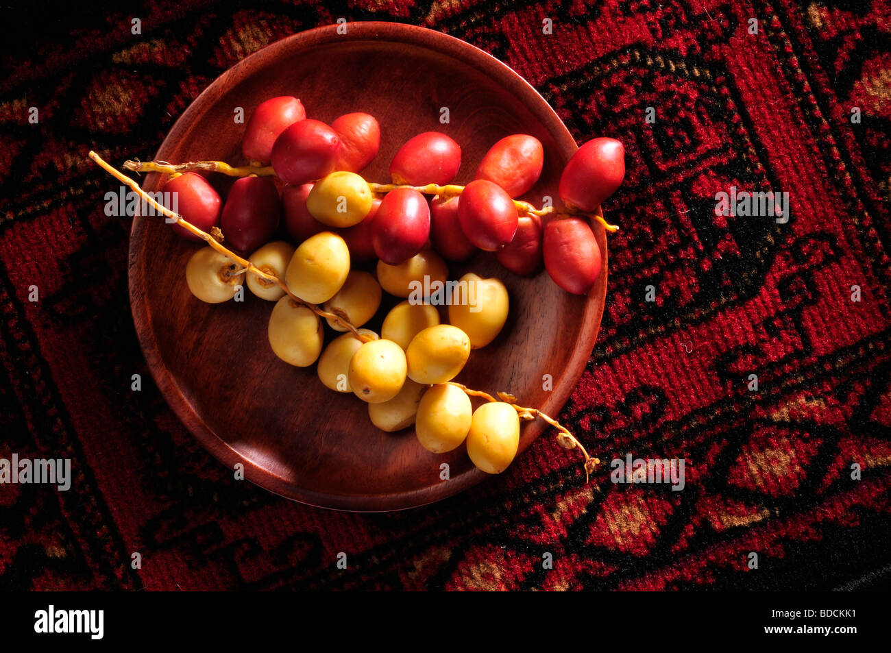 A bunch of yellow and red raw date in a wooden plate Stock Photo - Alamy