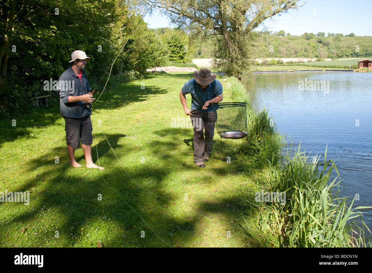 Fisherman catching a trout at Meon Springs trout fishery, Hampshire ...