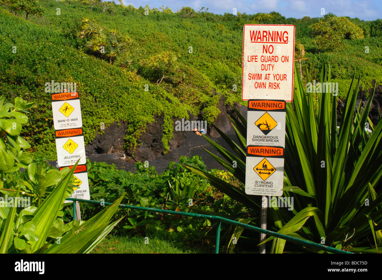 Warning signs at the start of the path to black sand beach ...