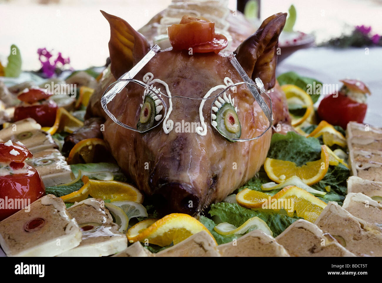 Grilled suckling pig decorated with glasses on a plate with pate, cold ...