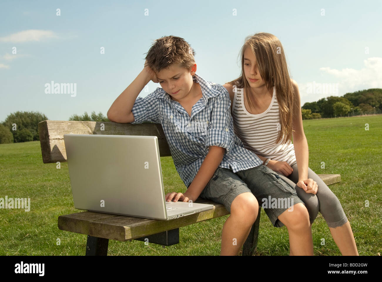 children sitting on a bench using a laptop computer Stock Photo - Alamy