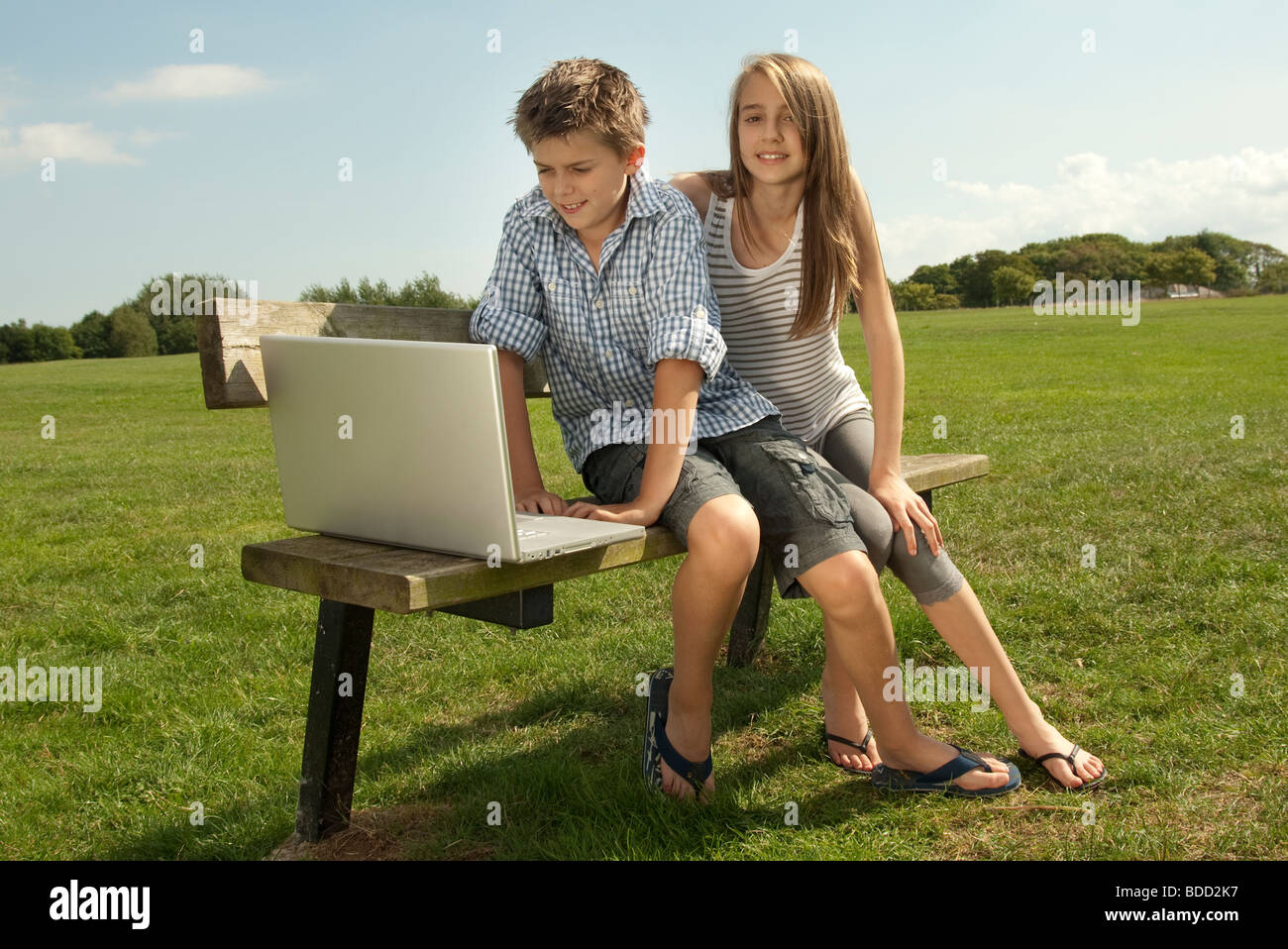 children sitting on a bench using a laptop computer Stock Photo - Alamy