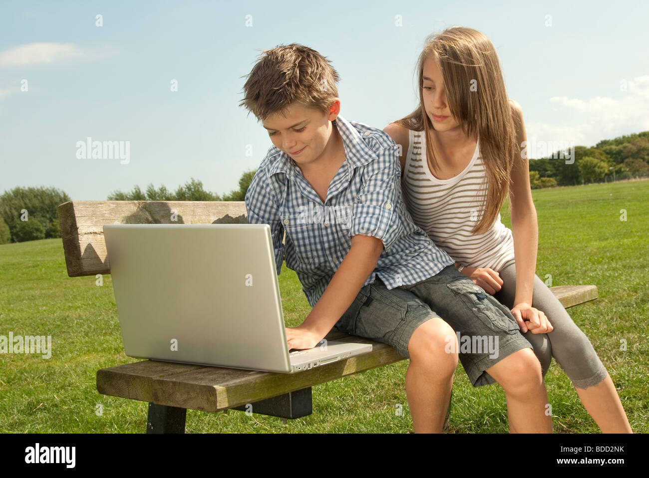 children sitting on a bench using a laptop computer Stock Photo - Alamy