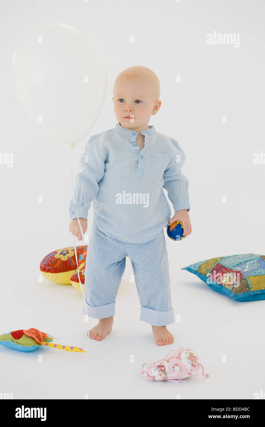 Baby boy standing with toys Stock Photo - Alamy
