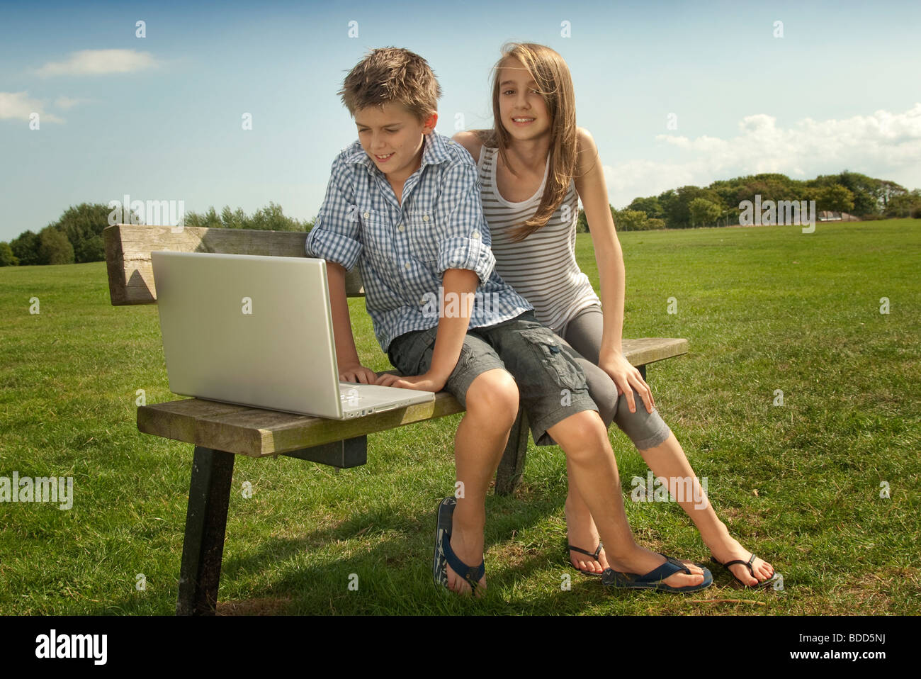 children sitting on park bench with laptop Stock Photo - Alamy