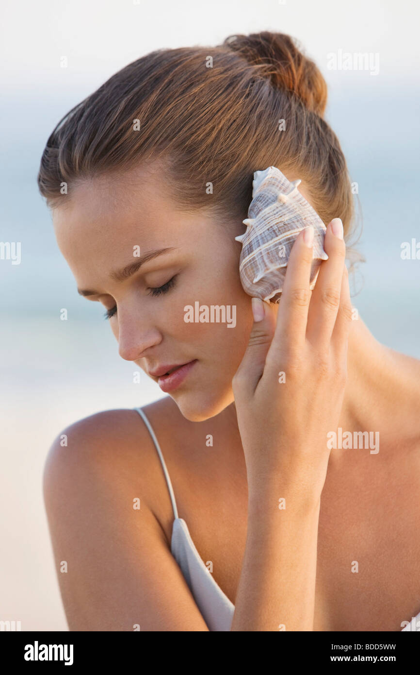 Woman listening to a conch shell Stock Photo - Alamy