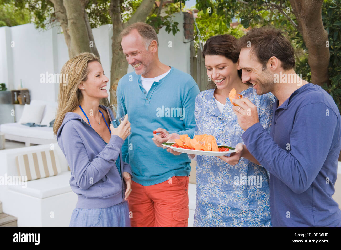 Four friends eating fruits and having fun Stock Photo - Alamy