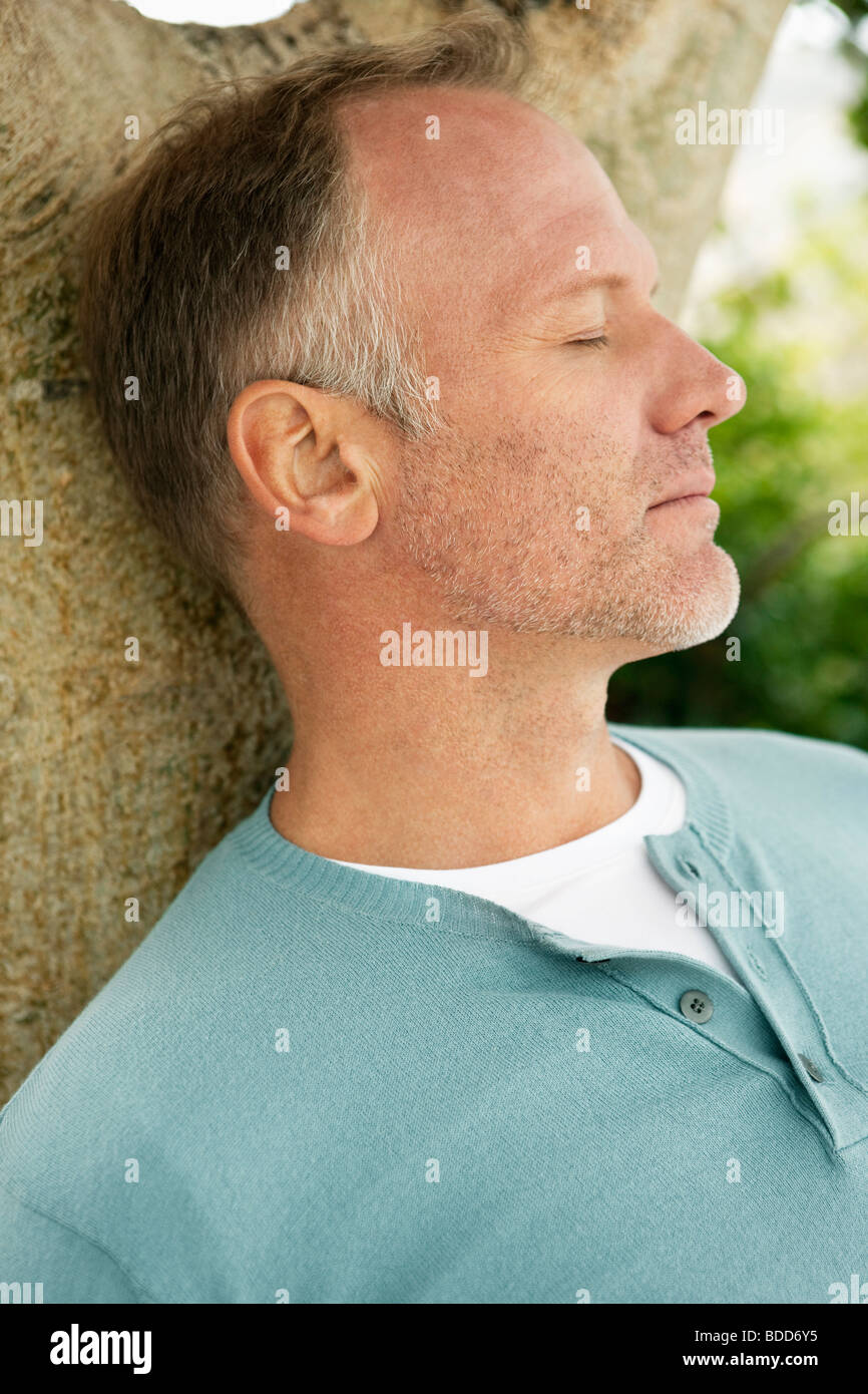 Man leaning against a tree and thinking Stock Photo - Alamy