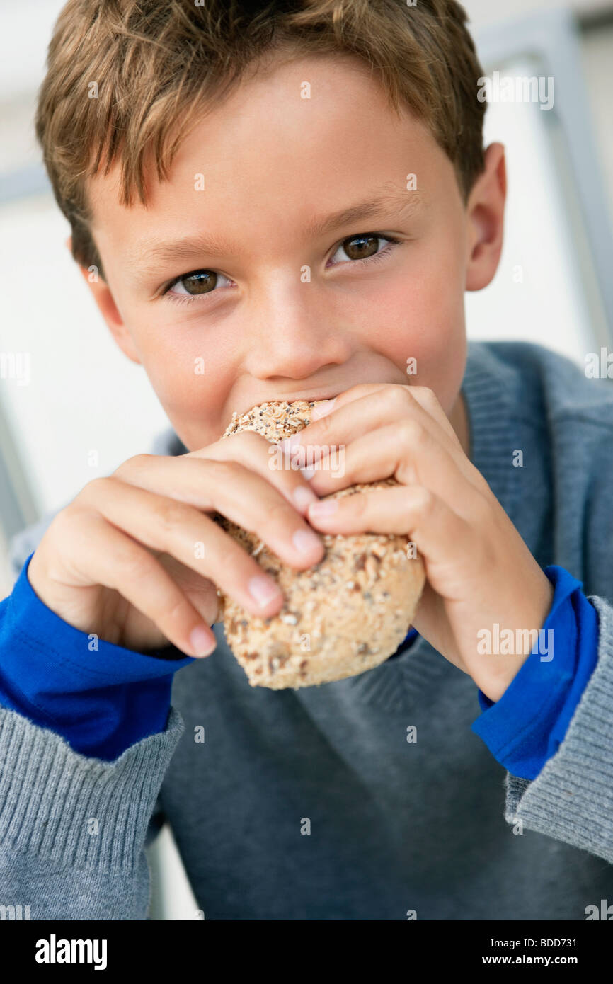 Portrait of a boy eating a bun Stock Photo - Alamy