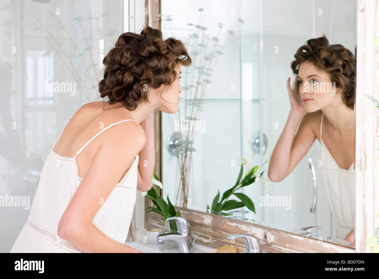 Woman examining her face in the mirror Stock Photo - Alamy
