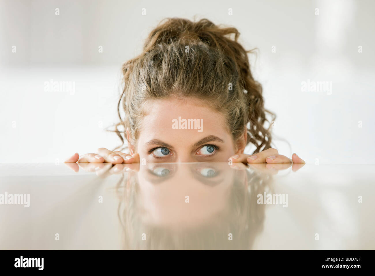 Woman peeking over a dining table Stock Photo - Alamy