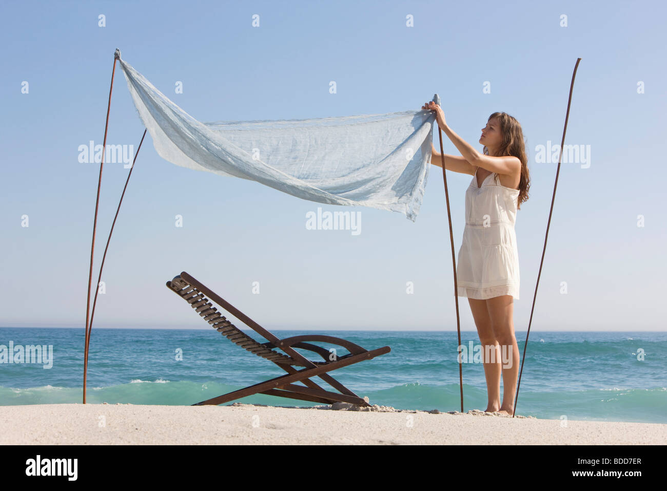 Woman fixing a canopy on the beach Stock Photo - Alamy