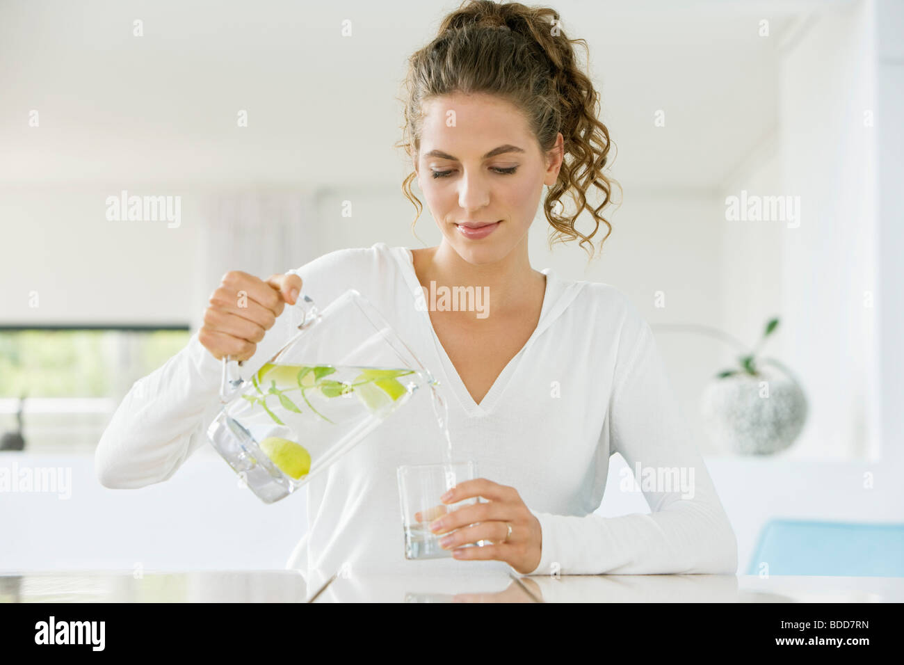 Woman pouring lemonade into a glass from a jug Stock Photo - Alamy