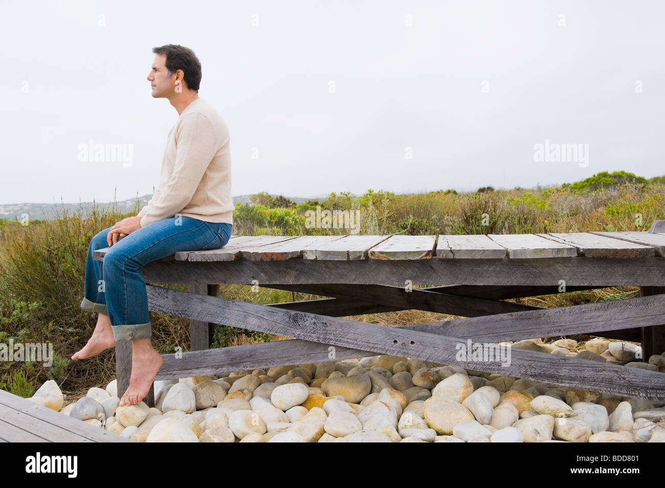 Man sitting on a boardwalk and thinking Stock Photo - Alamy