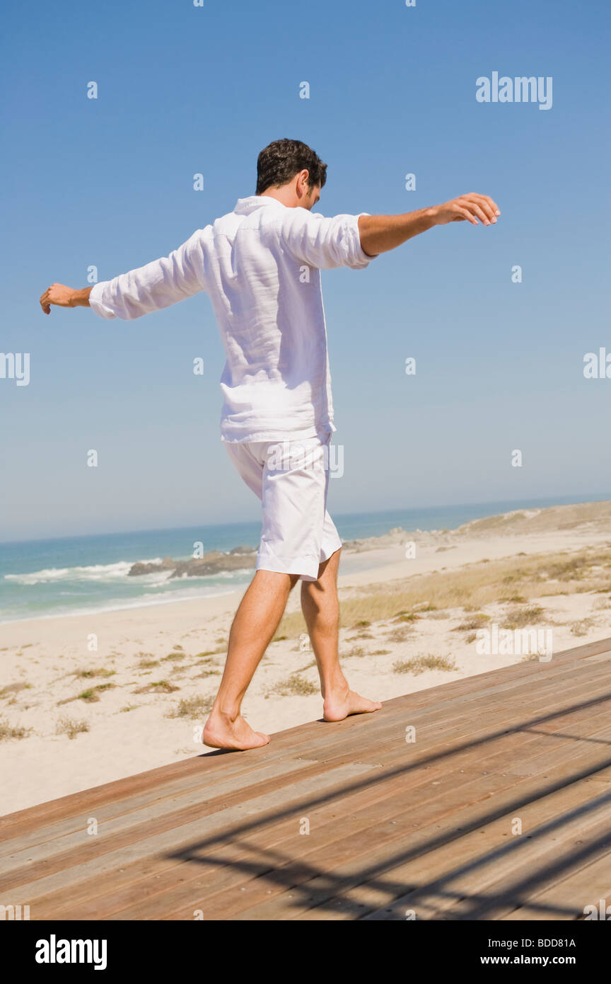 Man walking on a boardwalk on the beach Stock Photo - Alamy
