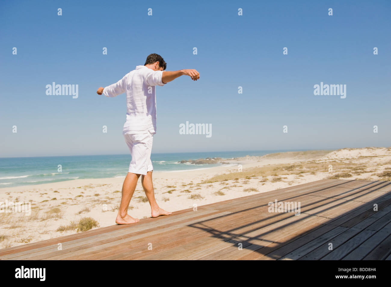 Man walking on a boardwalk on the beach Stock Photo - Alamy