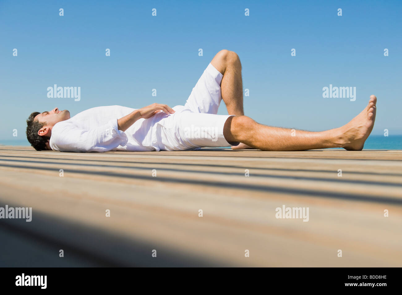 Man lying on a boardwalk on the beach Stock Photo - Alamy