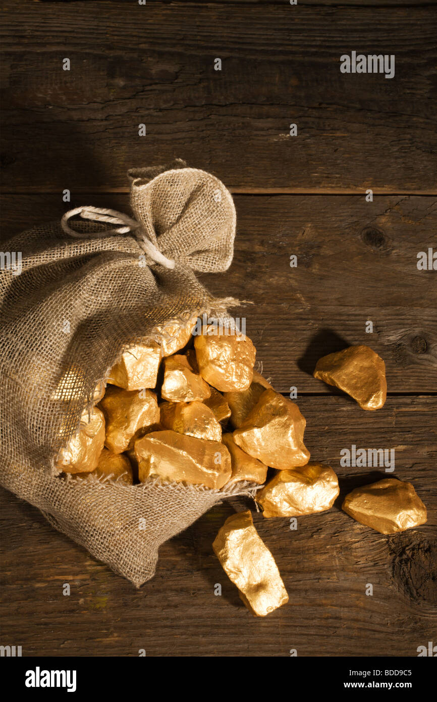 Heavy gold spilling out from a torn bag Stock Photo - Alamy